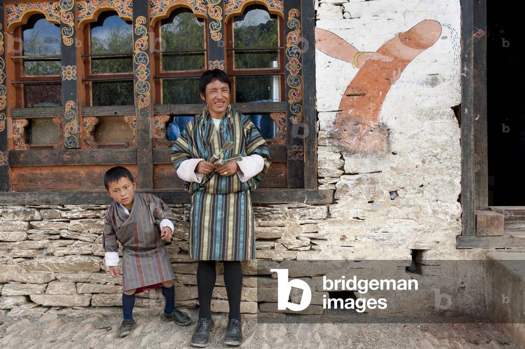 Image of Father and son standing in front of house wall with