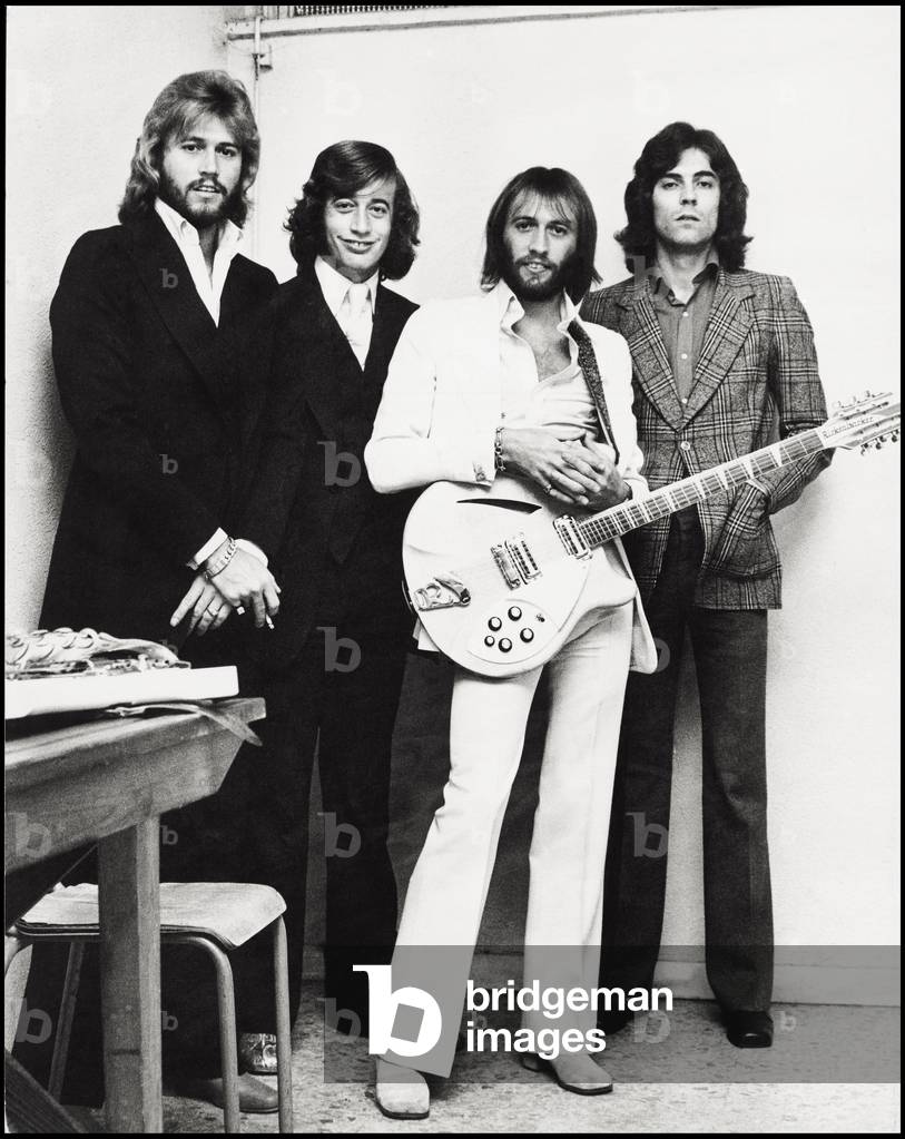 Image of The Bee Gees musical group posing with a guitar. The