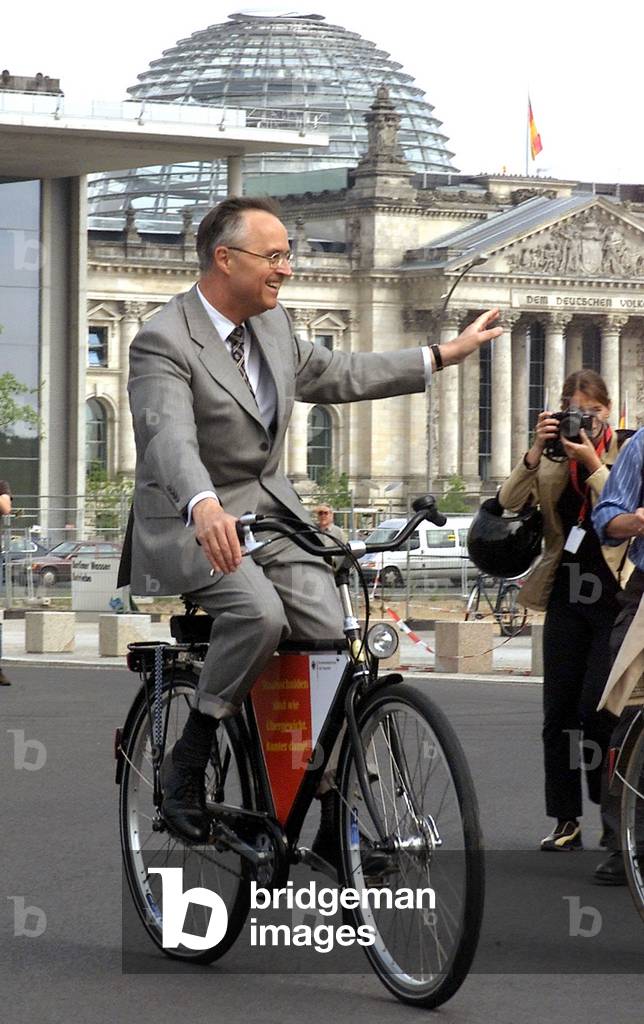 Image of German Finance Minister Hans Eichel rides a push bike beside