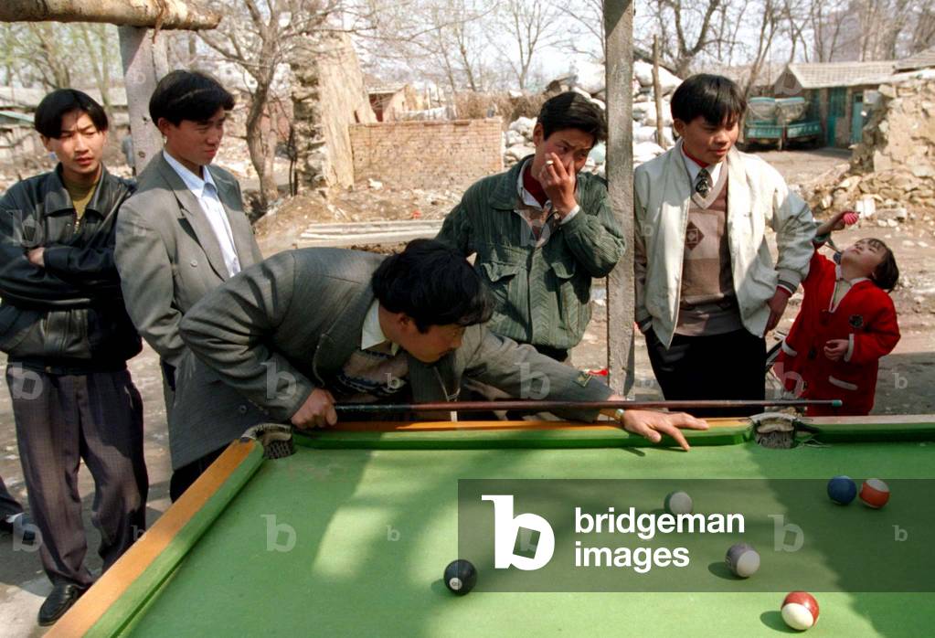 Image of Chinese men play a game of eight-ball at an outdoor