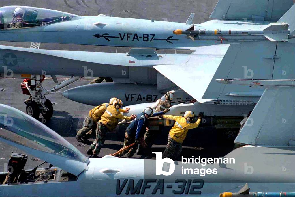 Image of US navy support crews work on a US F18 Hornet