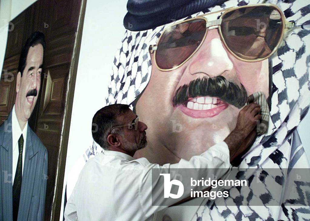 Image of An Iraqi cleans a large picture of President Saddam Hussein