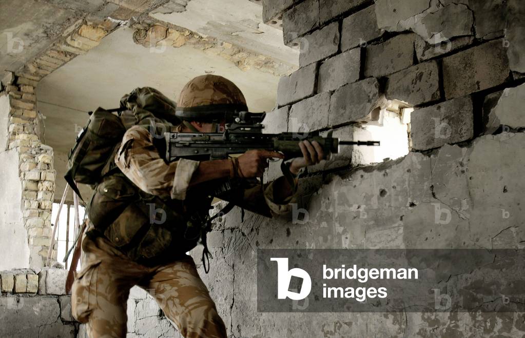 Image of A BRITISH SOLDIER LOOKS OUT OF A BUILDING AFTER COMING