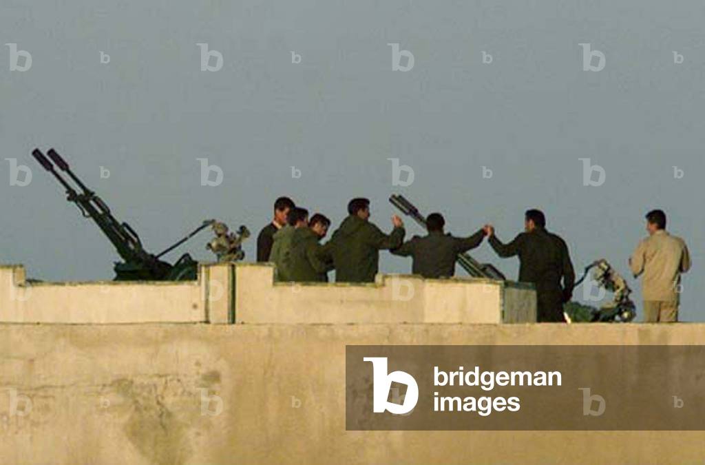 Image of Iraqi soldiers dance beside their anti-aircraft gun on top of