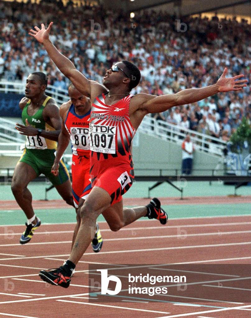Image of Ato Boldon of Trinidad spreads his arms as he crosses