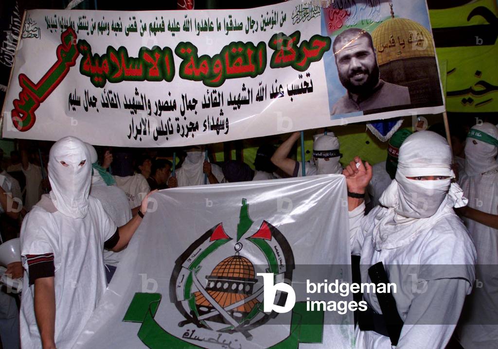 Image of Masked Palestinian and supporters of the Hamas movement hold a