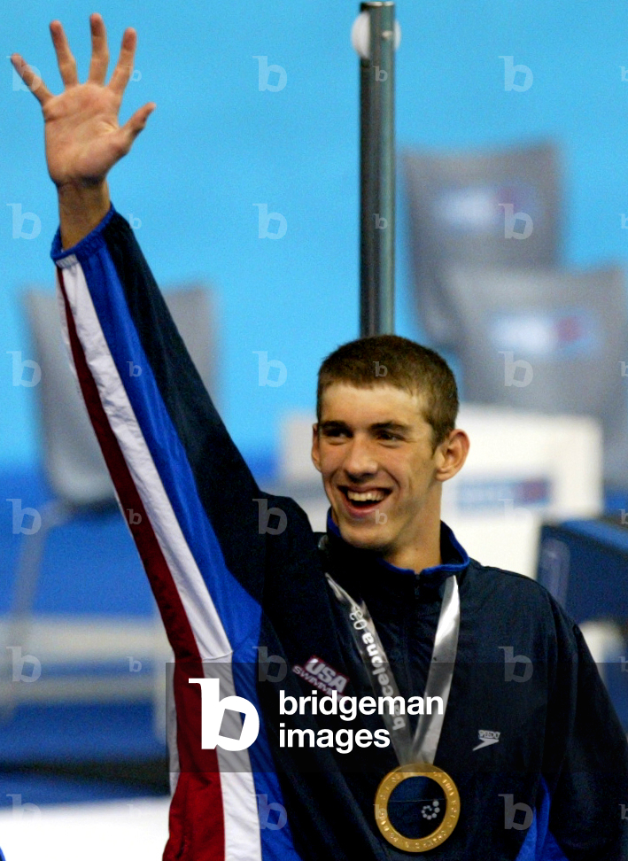 Image of USA'S MICHAEL PHELPS WAVES WITH HIS GOLD MEDAL AFTER WINNING