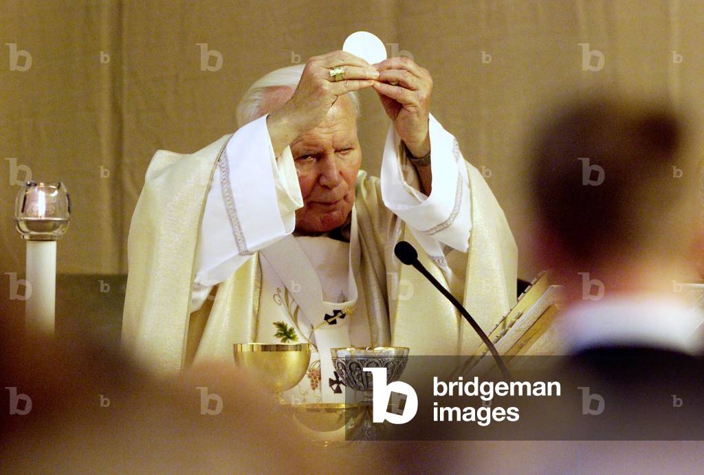 Image of Pope John Paul II holds up the communion host to