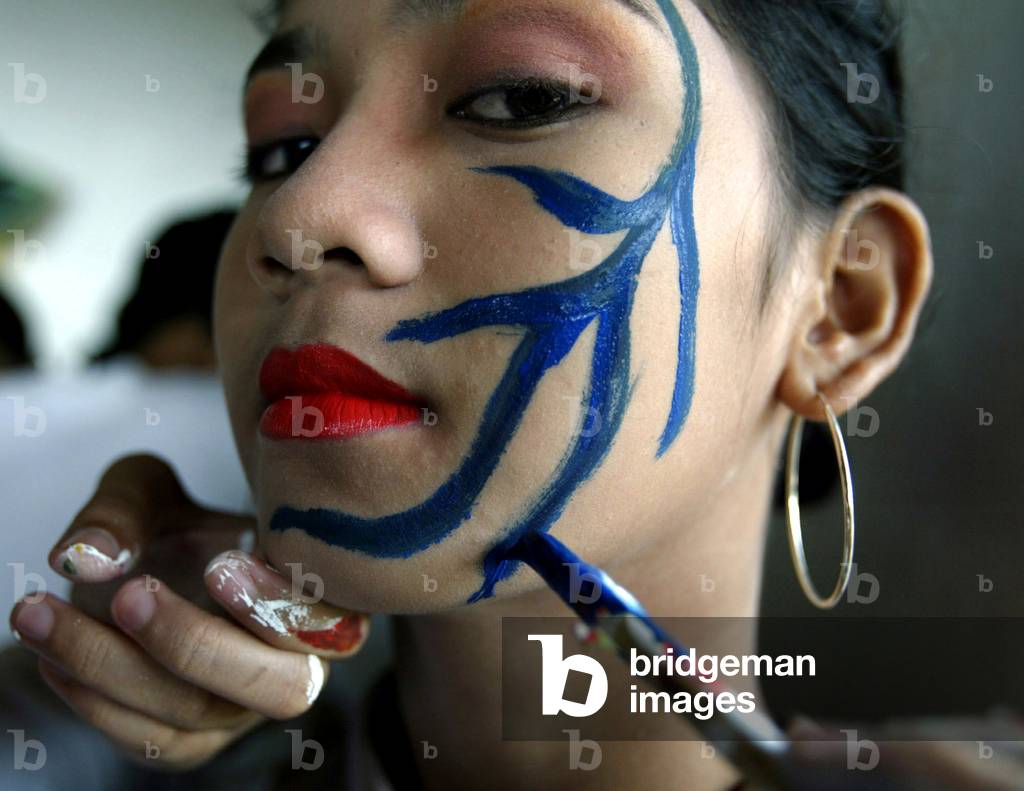 Image of A Filipino woman gets her face painted during a festival