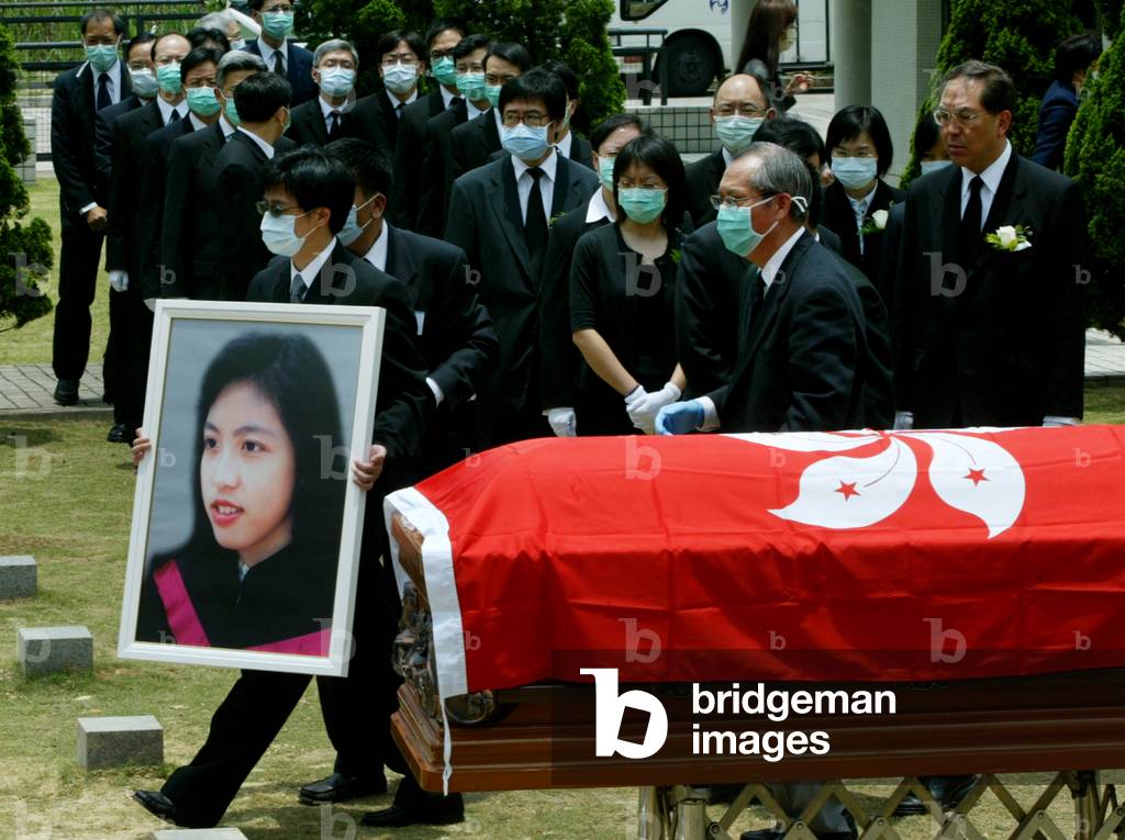 Image of MOURNERS STAND BEHIND FLAG-DRAPED CASKET AT FUNERAL OF A DOCTOR