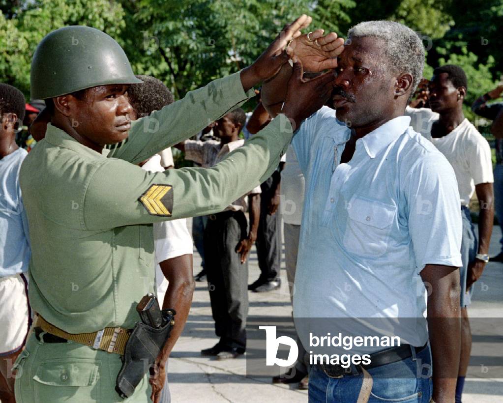 Image of A member of the Haitian army shows a new recruit