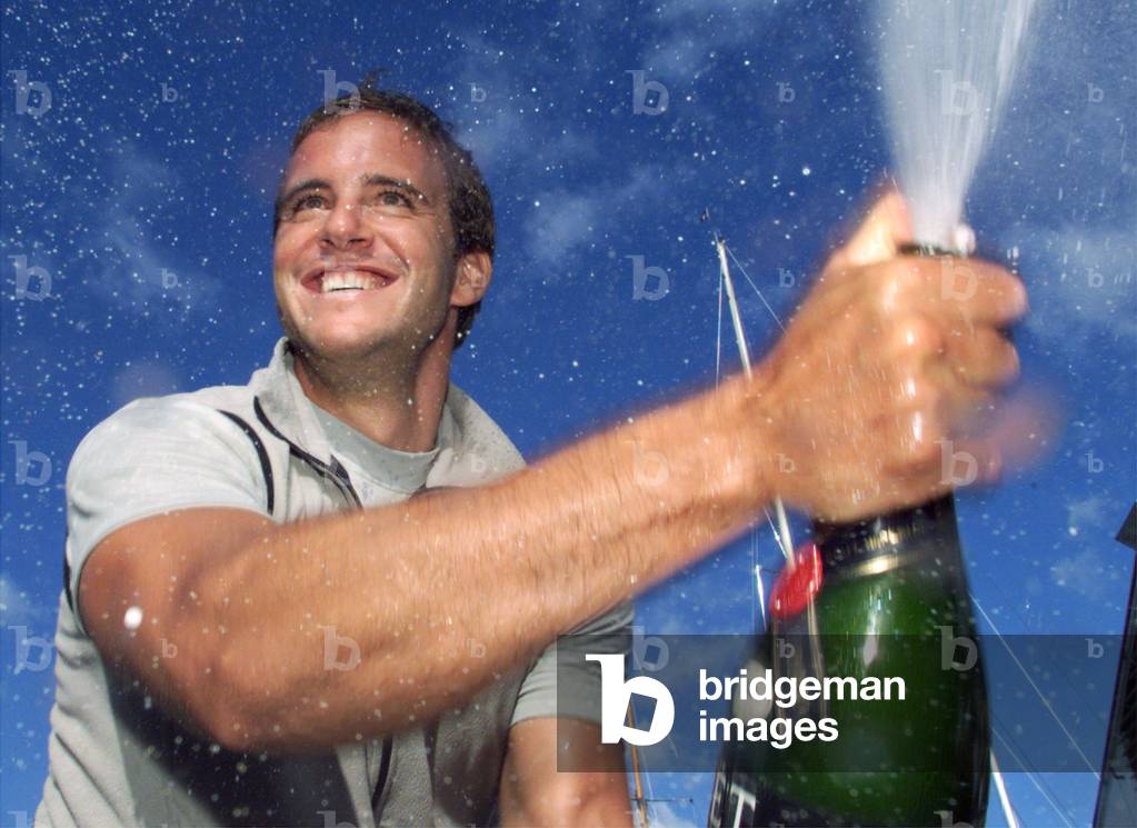 Image of Prada crew member Simone de Mari sprays champagne on the