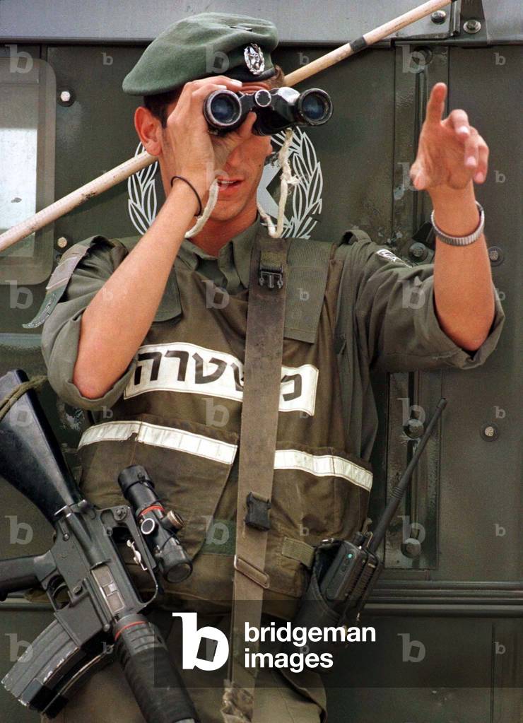 Image of An Israeli Border policeman keeps an eye on Palestinians who