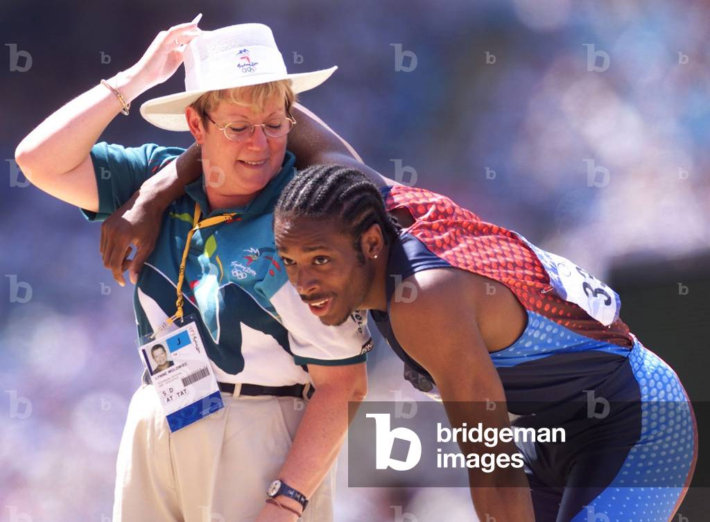 Image of ANGELO TAYLOR OF THE U.S. IS SUPPORTED BY A STEWARDESS