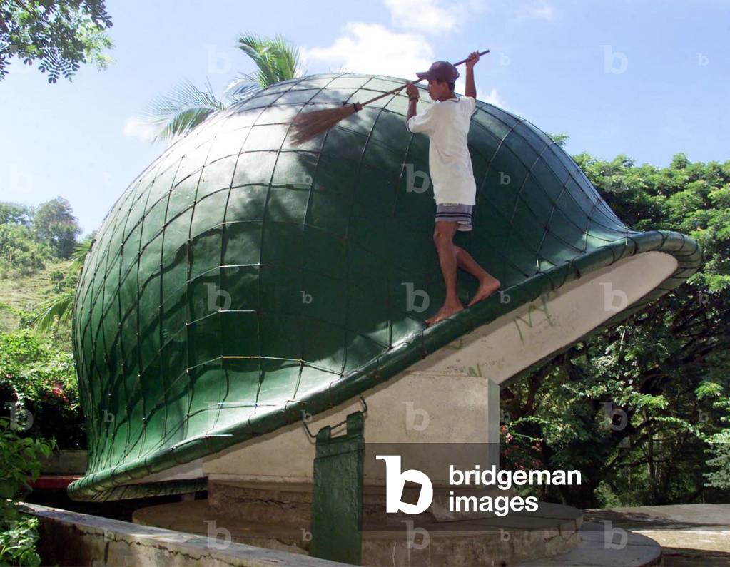 Image of A Filipino worker cleans a huge stone helmet with a