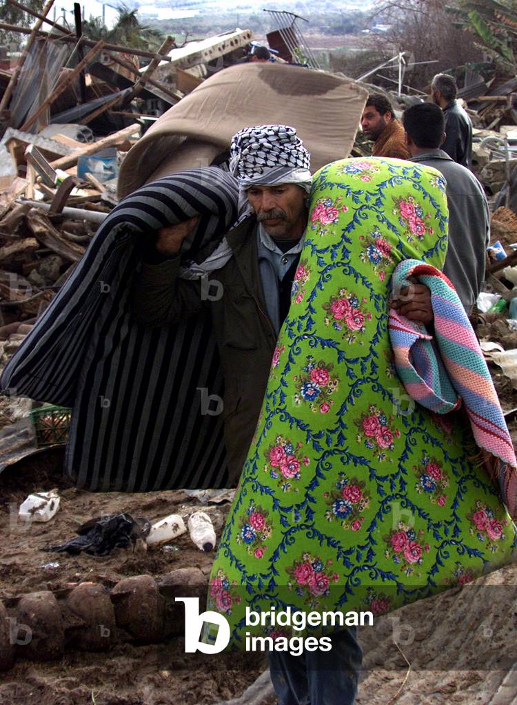 Image of A Palestinian man removes the remains of his house after