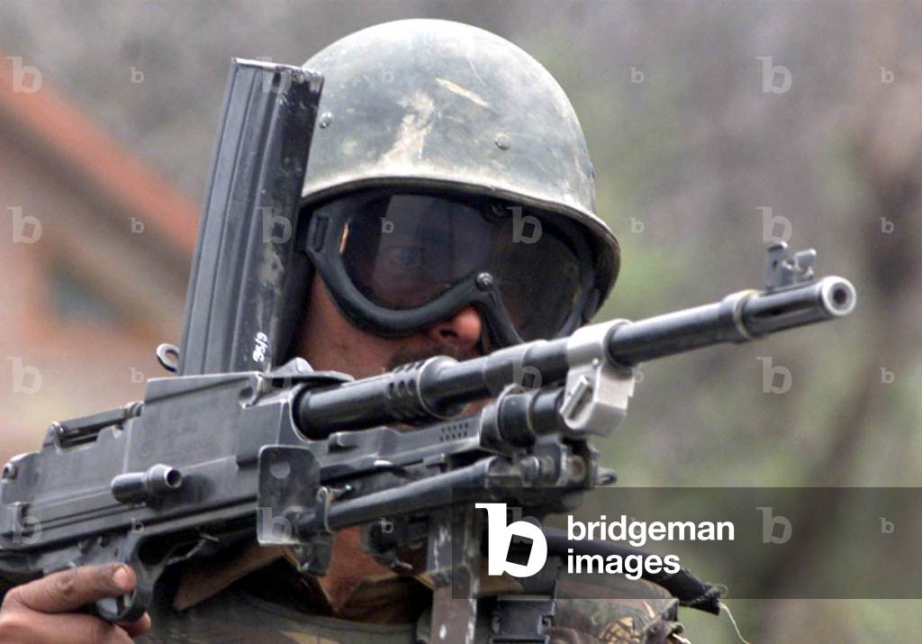 Image of An Indian para-military trooper with a Light Machine Gun keeps