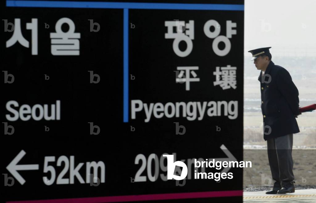 Image of A SOUTH KOREAN RAILROAD OFFICIAL STANDS NEAR A SIGNPOST ...