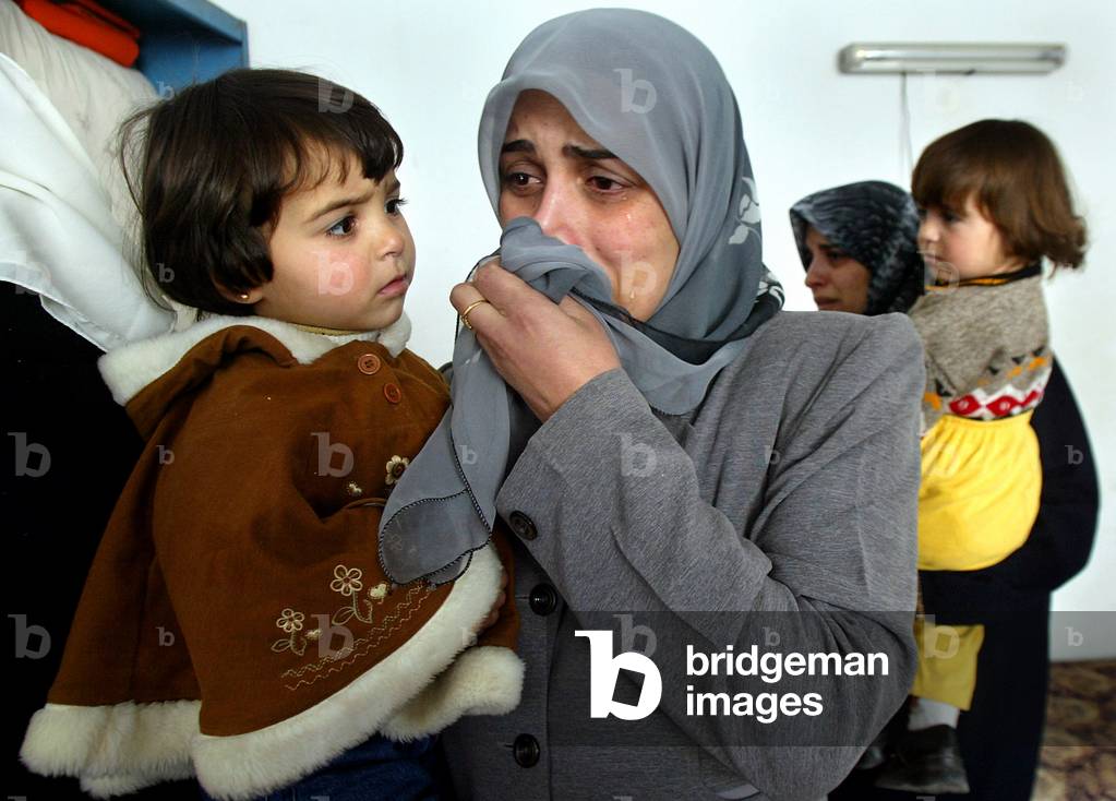 Image of A PALESTINIAN CHILD LOOKS AT HER MOTHER AS SHE CRIES