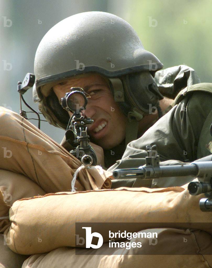 Image of AN ISRAELI SOLDIER POINTS HIS GUN AT PALESTINIANS IN THE
