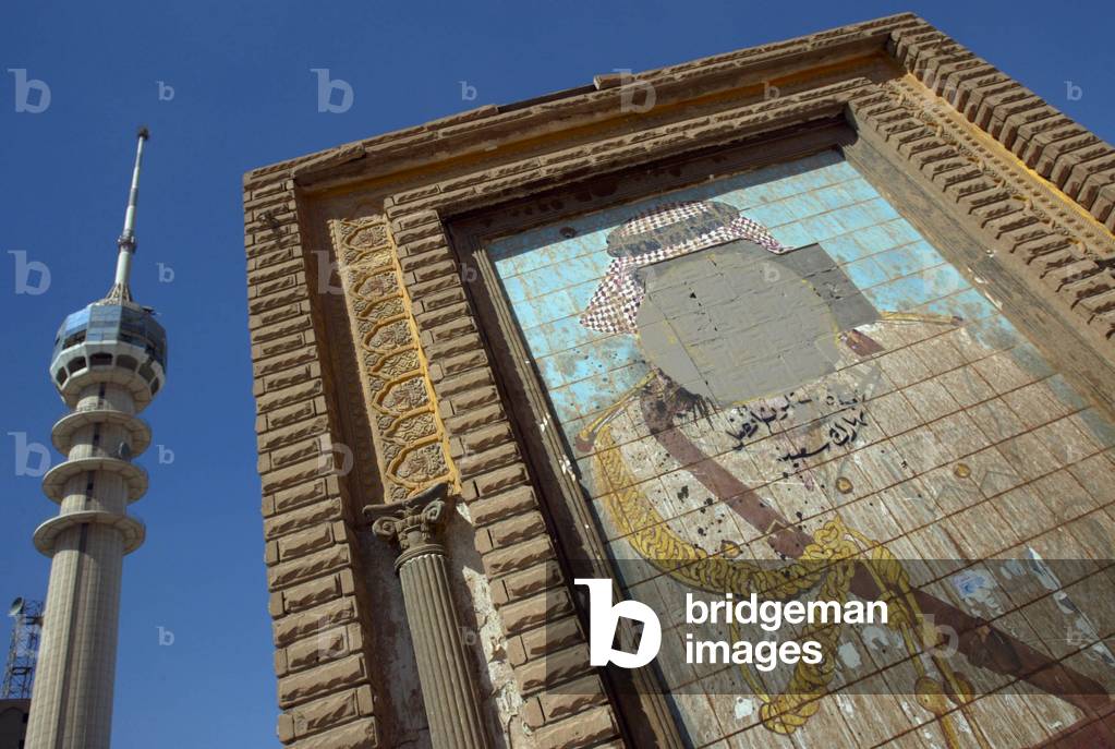 Image of DEFACED PORTRAIT OF SADDAM HUSSEIN REMAINS UNDER TOWER OF HIS
