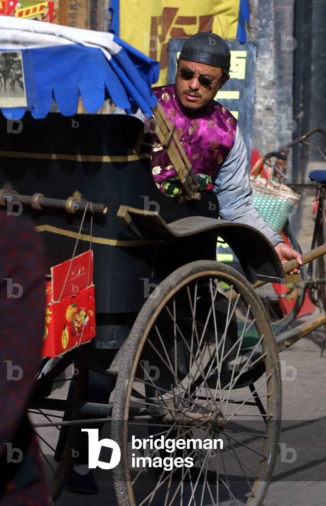 Image of A rickshaw driver in traditional costume waits for tourists who