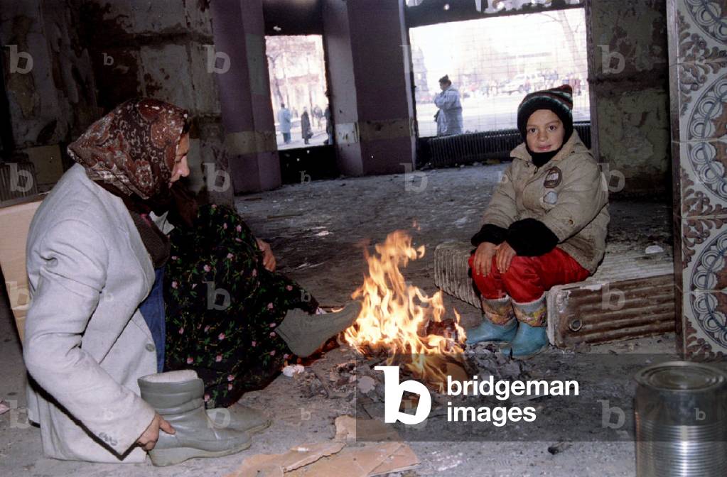 Image of A gypsy woman and her son sit in a destroyed