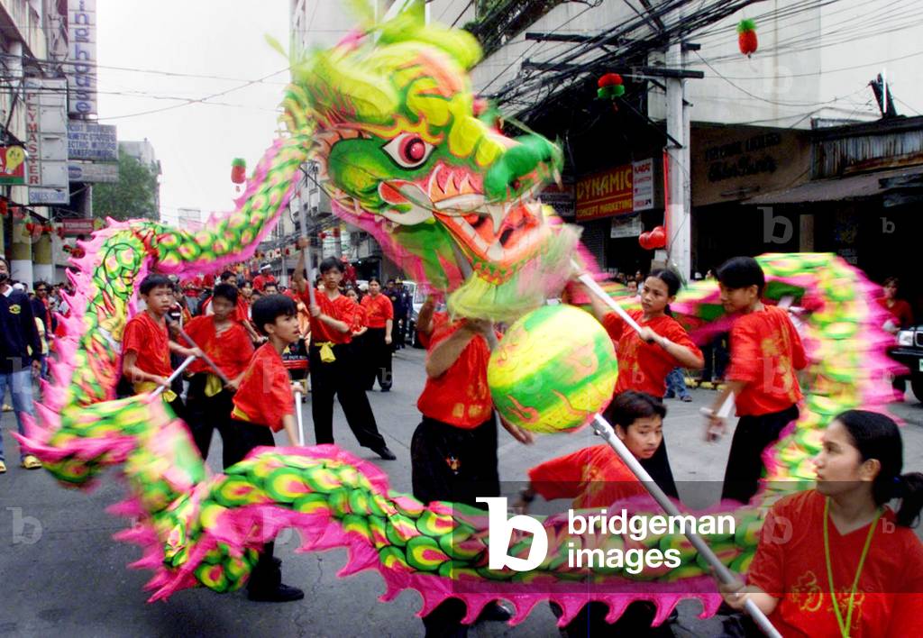 Image of Filipino-Chinese students hold a dragon and dance in the streets
