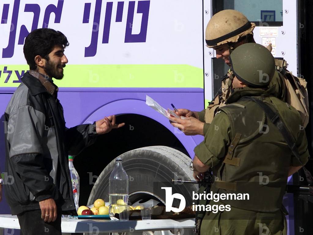 Image of A ISRAELI SOLDIER CHECKS THE IDENTITY OF A PALESTINIAN MAN