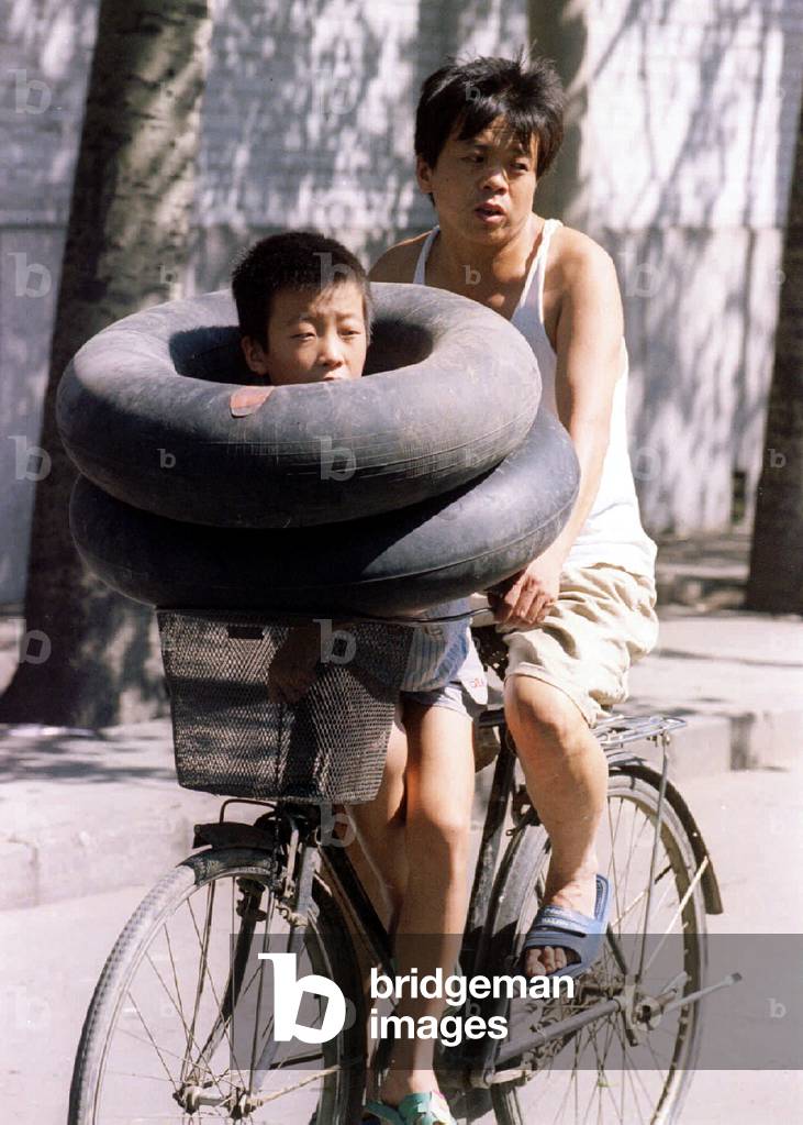Image of A young boy "carries" inner tubes of car tyres as