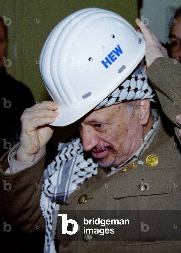 Image of PLO Chairman Yassir Arafat puts on a safety helmet during