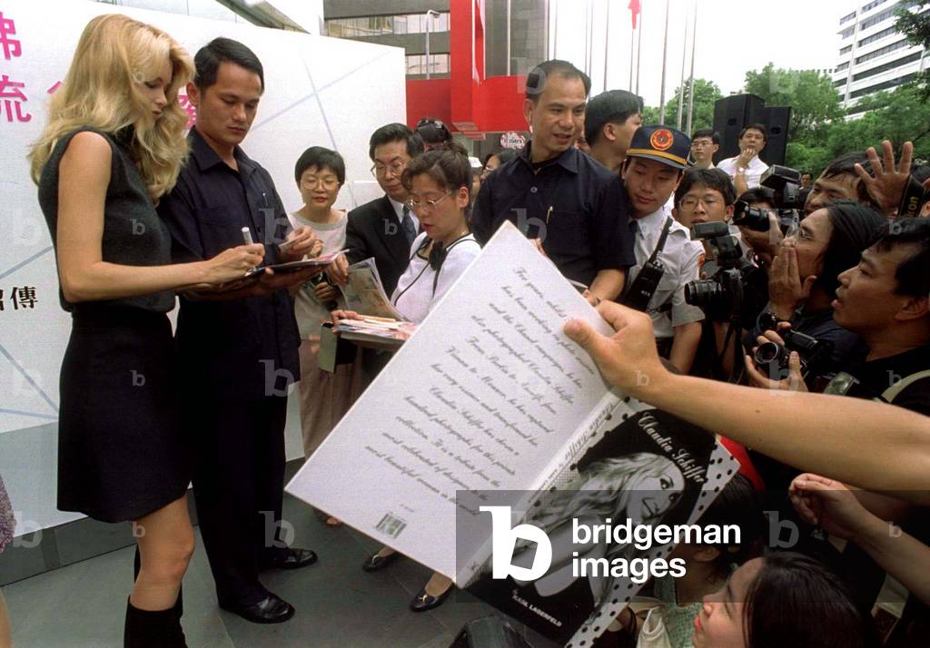 Image of Supermodel Claudia Schiffer signs an autograph for a fan as