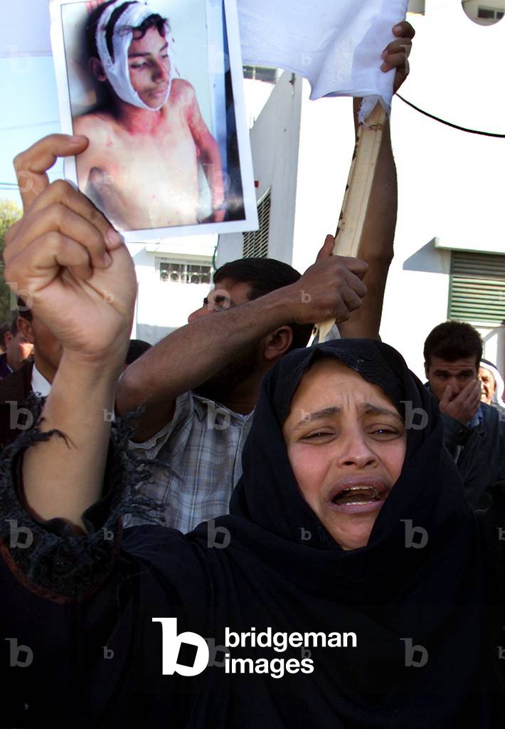 Image of A Palestinian woman holds a picture of her son Asad