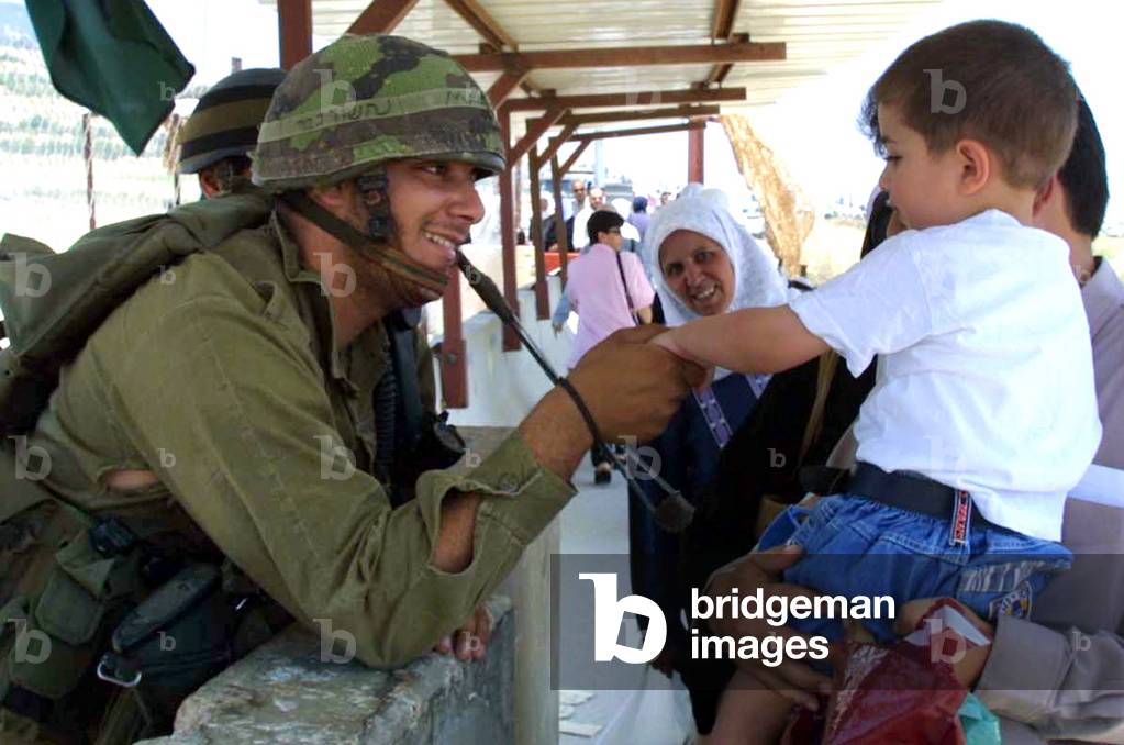 Image of AN ISRAELI SOLDIER PLAYS WITH A PALESTINIAN CHILD AT THE