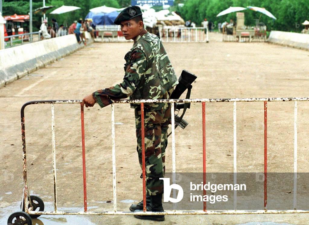 Image of A THAI SOLDIER GUARDS A CHECKPOINT AT THE THAI BORDER