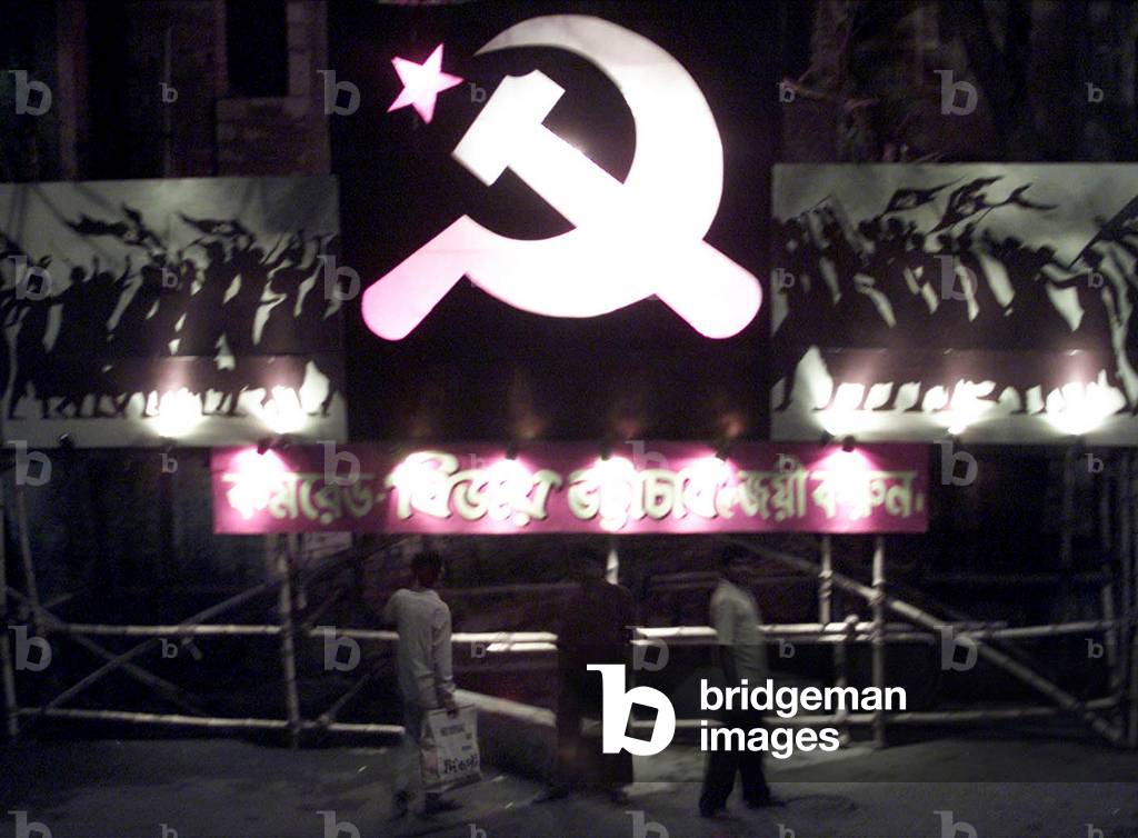 Image of PEOPLE WALK BESIDE ILLUMINATED CUT-OUTS OF THE SYMBOL OF THE