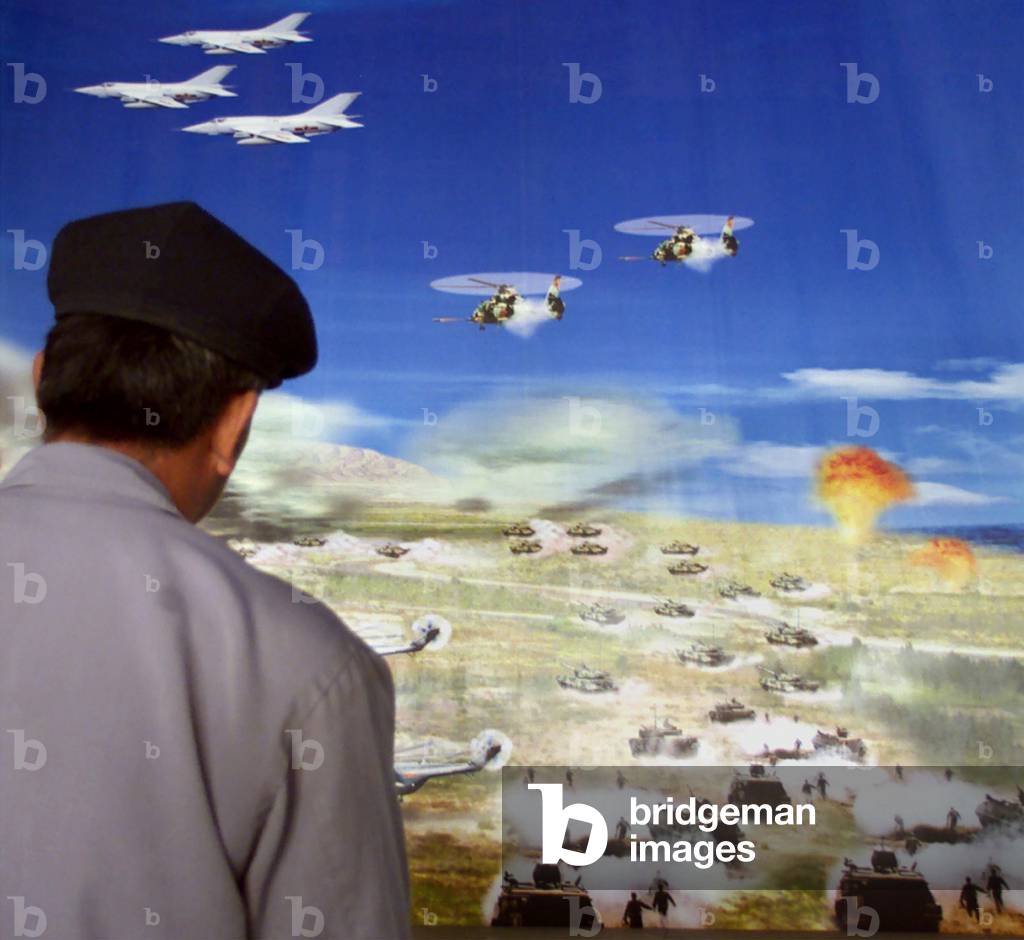 Image of CHINESE MAN LOOKS AT A PAINTING DEPICTING PLA SOLDIERS ATTACKING