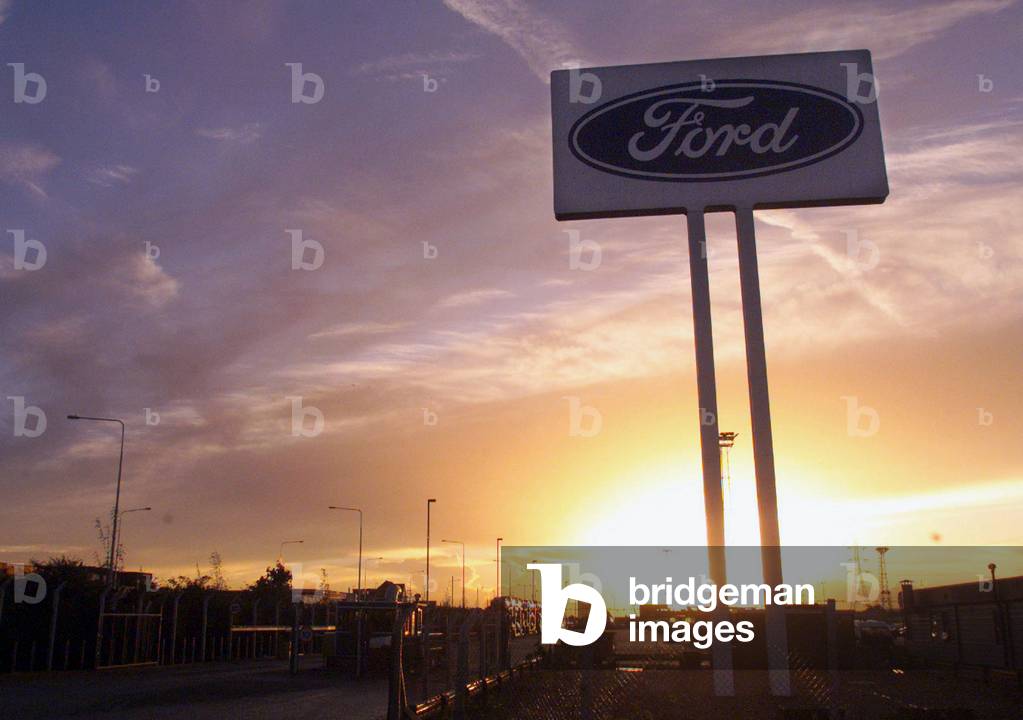 Image of The sun rises behind a giant Ford sign that stands