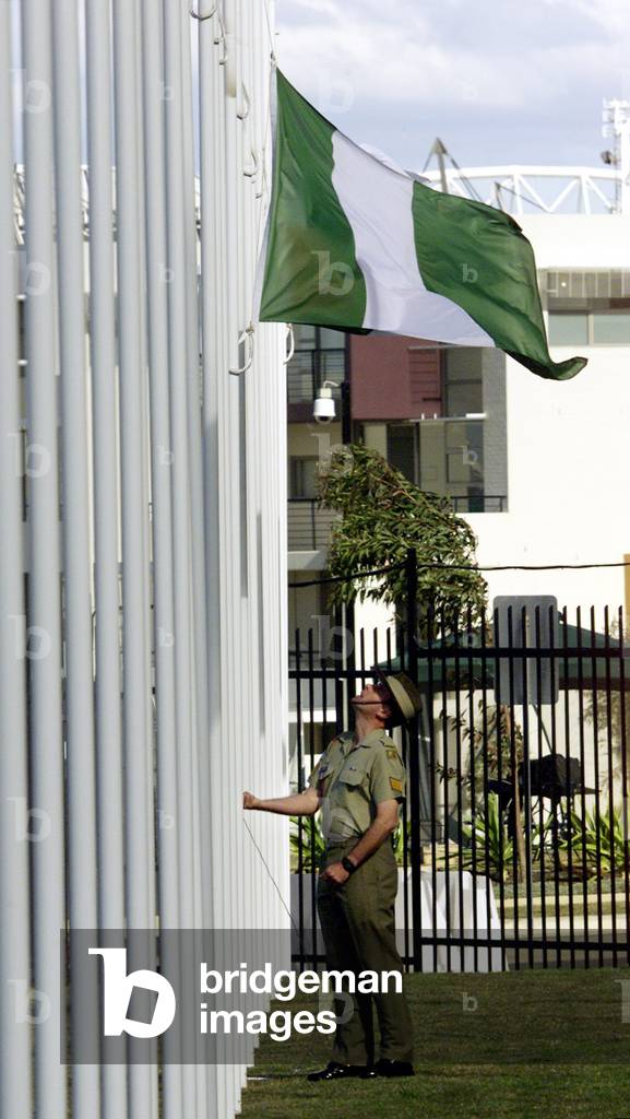 Image of AN AUSTRALIAN SOLDIER LOWERS THE NIGERIAN FLAG TO HALF MAST