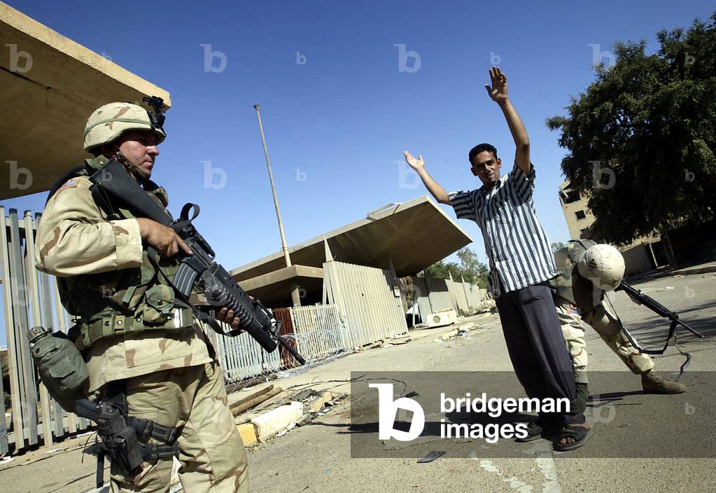Image of A looter is searched by U.S. army soldiers after he