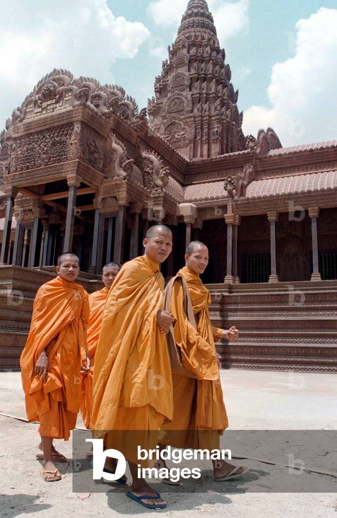 Image of Cambodian Buddhist monks walk past a replica of Cambodia's ancient