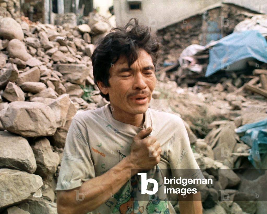 Image of A MAN CRIES IN FRONT OF THEIR HOUSE DAMAGE IN