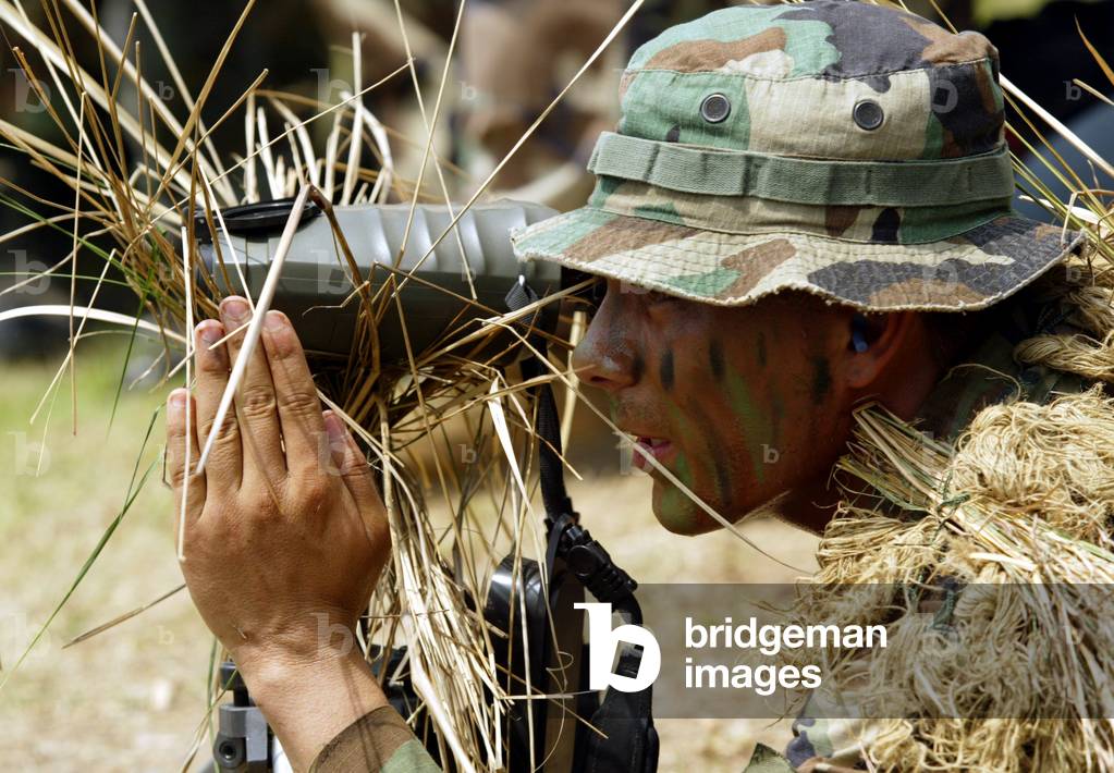 Image of A US SOLDIER PEEPS THROUGH A BINOCULAR DURING WAR GAMES