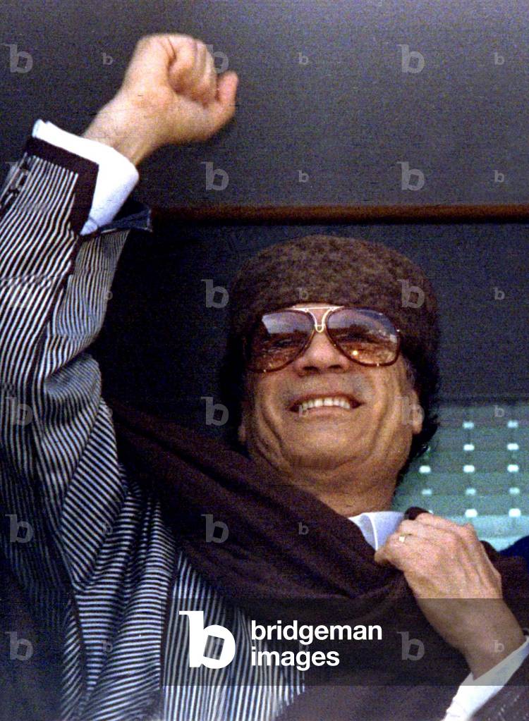 Image of Libyan leader Muammar Gaddafi waves to a crowd which gathered