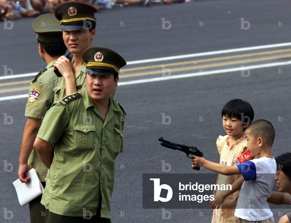 Image of A Chinese boy points a toy gun at a police