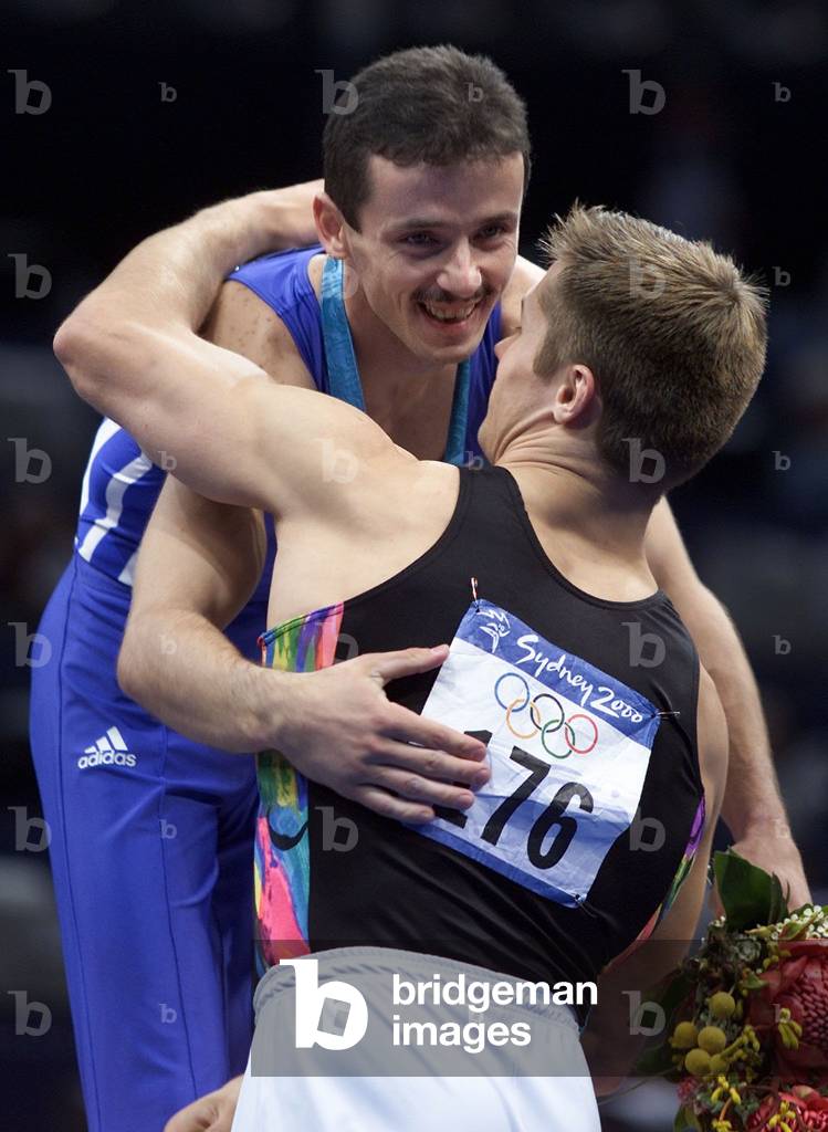 Image of MEDAL WINNERS IN THE POMMEL HORSE FINAL EMBRACE AT PODIUM,
