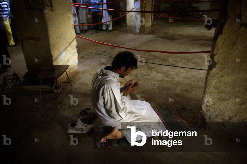 Image of An Afghan boxer prays after training in a small boxing