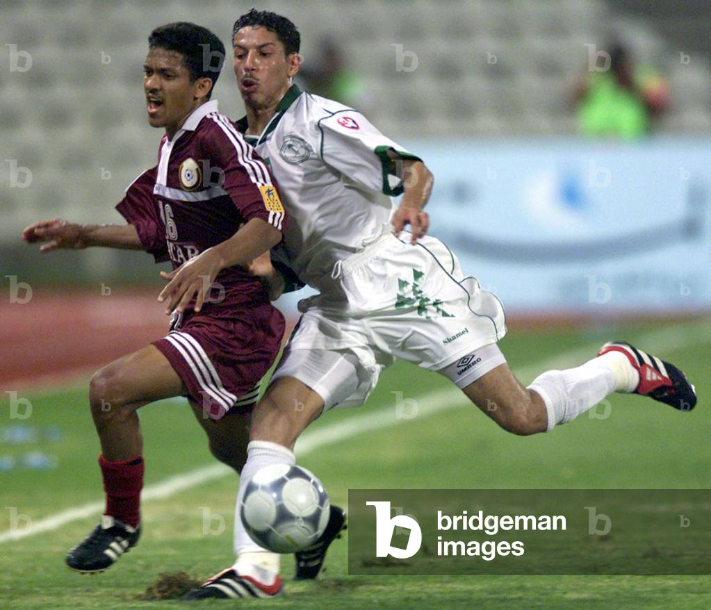 Image of GHOLAM OF QATAR IS TACKLED BY AL SAQRI OF SAUDI