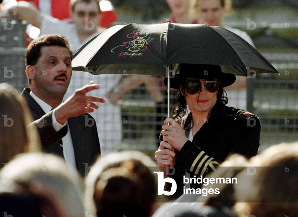 Image of Michael Jackson shades himself from the sun with an umbrella