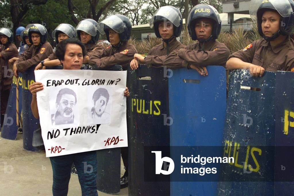 Image of A FILIPINO PROTESTER HOLDS A PLACARD IN FRONT OF RIOT